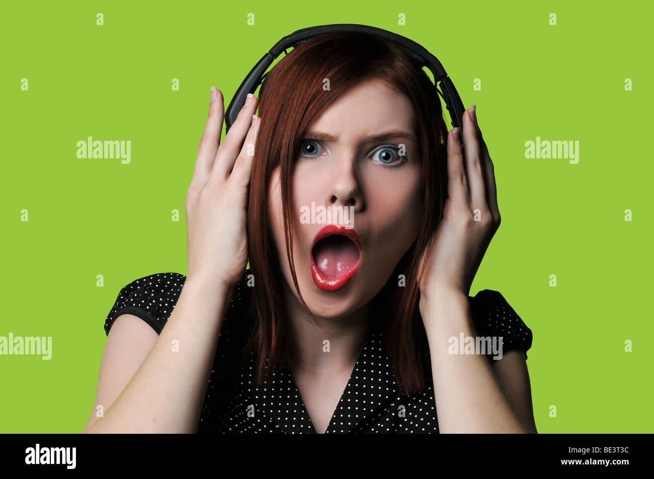 Young woman listening to loud music against a green background Stock ...