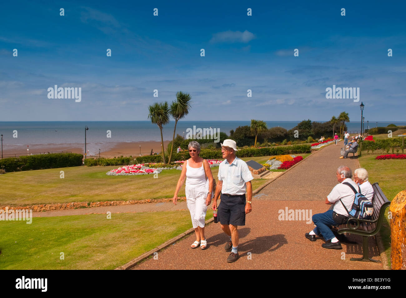 Two pensioners sitting on a seafront bench looking out to sea at ...