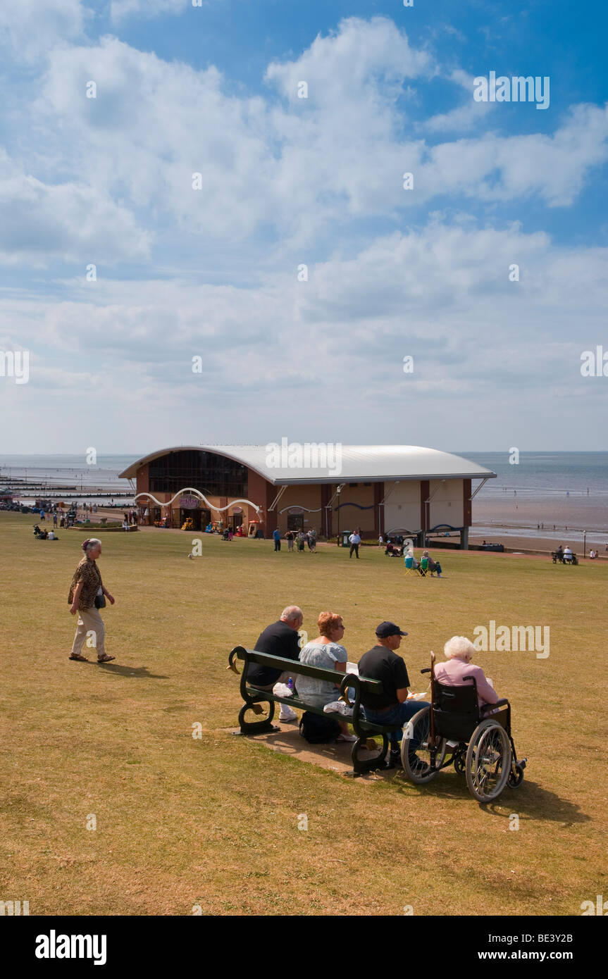 Holidaymakers sitting on a seafront bench looking out to sea at ...