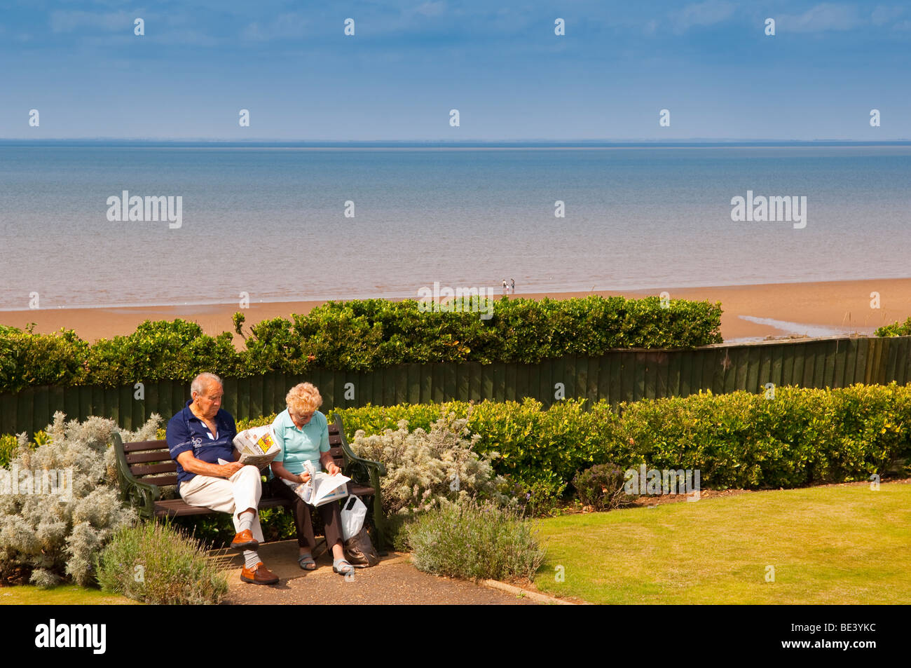 Two pensioners sitting on a seafront bench reading their newspapers at ...