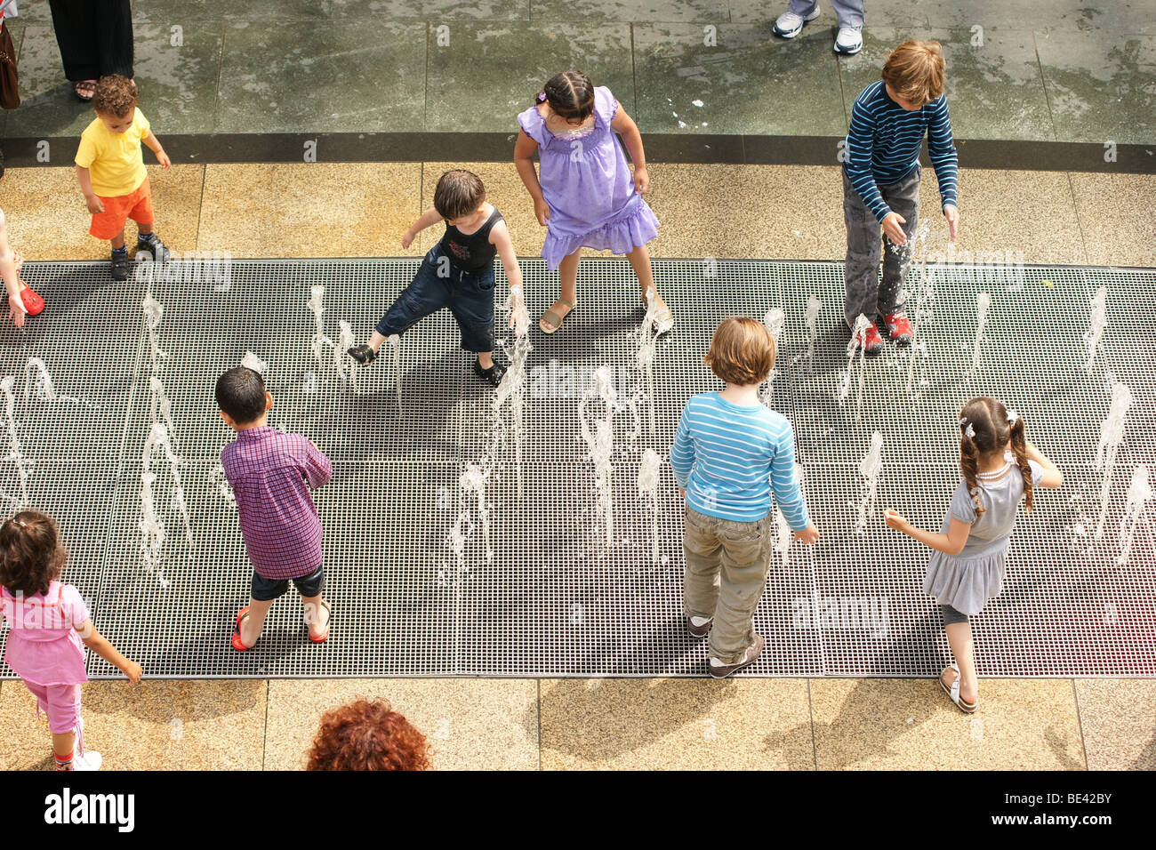 Group children running jumping playing frolicking in fountain between ...