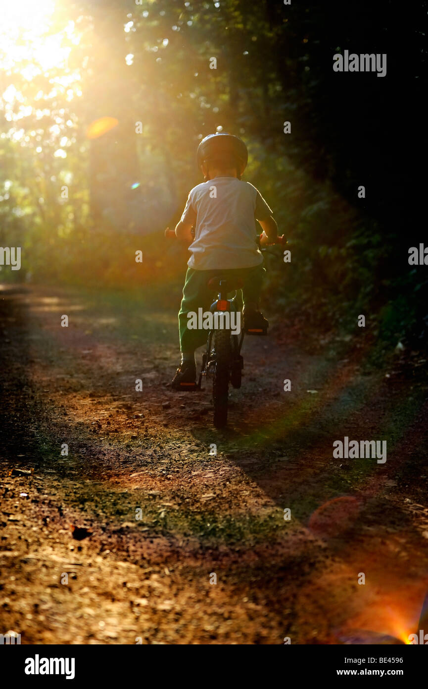 Child boy cycling through a forest bicycle ride with bike helmet Stock ...