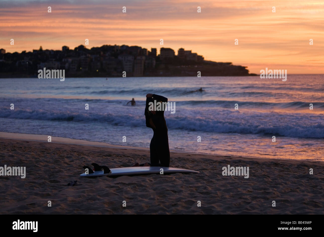Surfer stretching before a dawn surf at Bondi Beach. Sydney, New South ...