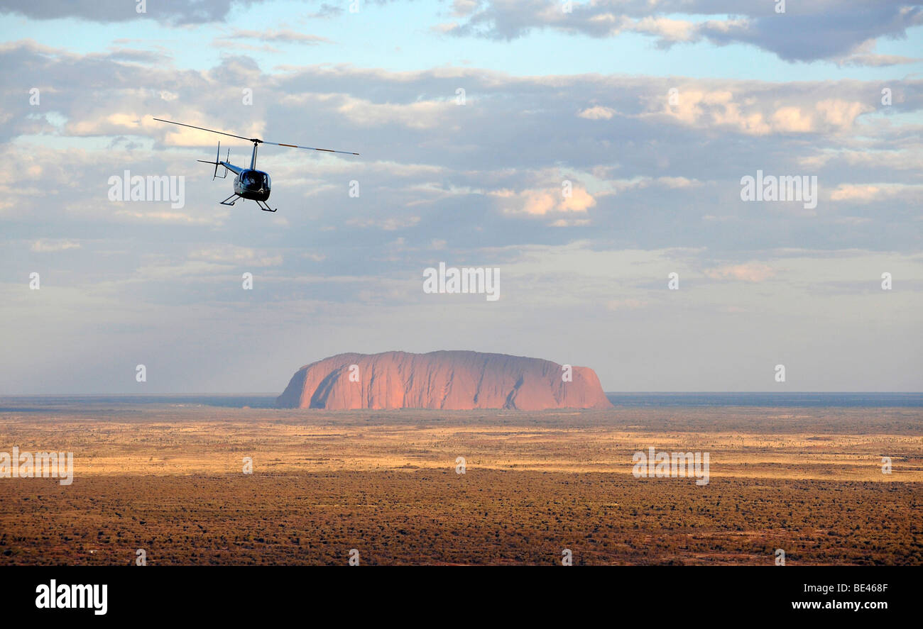 Aerial view of a helicopter in front of Uluru, Ayers Rock at sunset ...