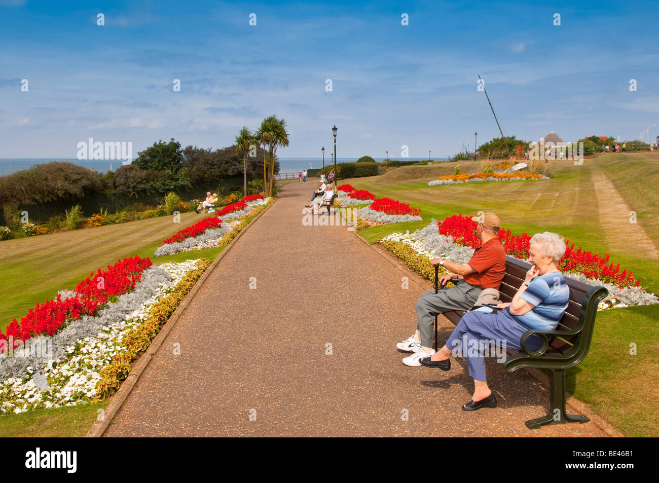 Two pensioners sitting on a seafront bench looking out to sea at ...