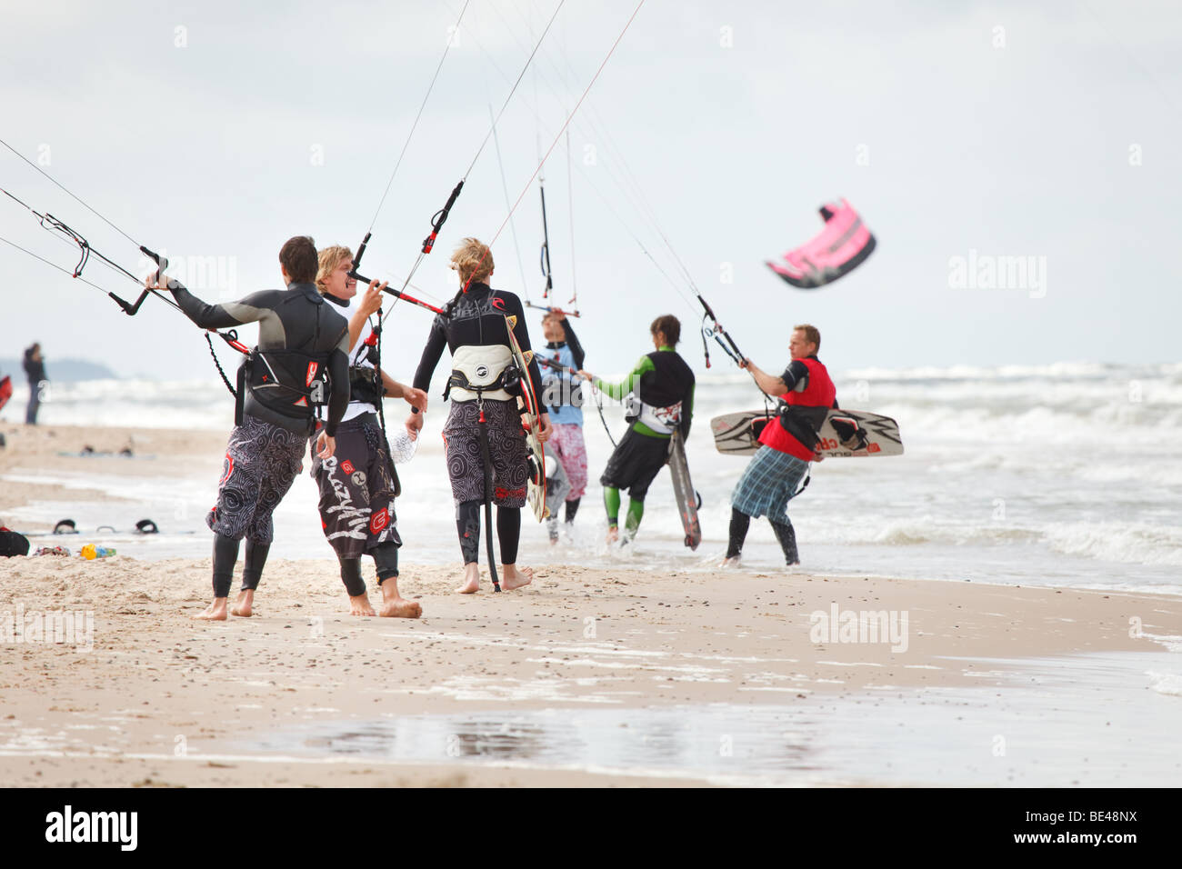 Kiteboarding competition with many active people and kites flying high ...