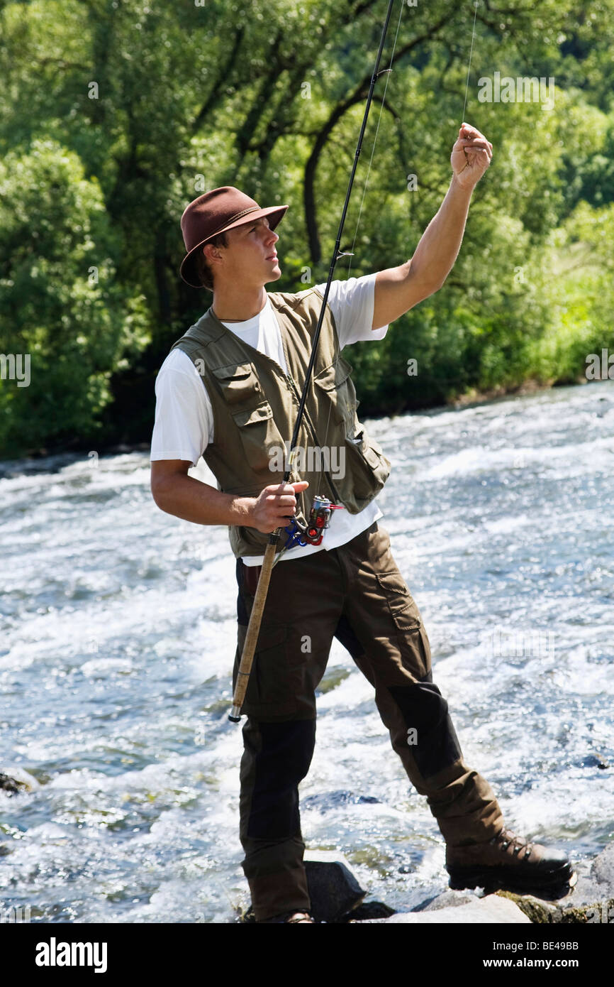 Anglerwith rod at the water, waterfall Stock Photo - Alamy