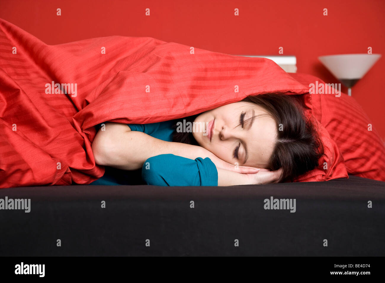Young woman under red blanket Stock Photo - Alamy