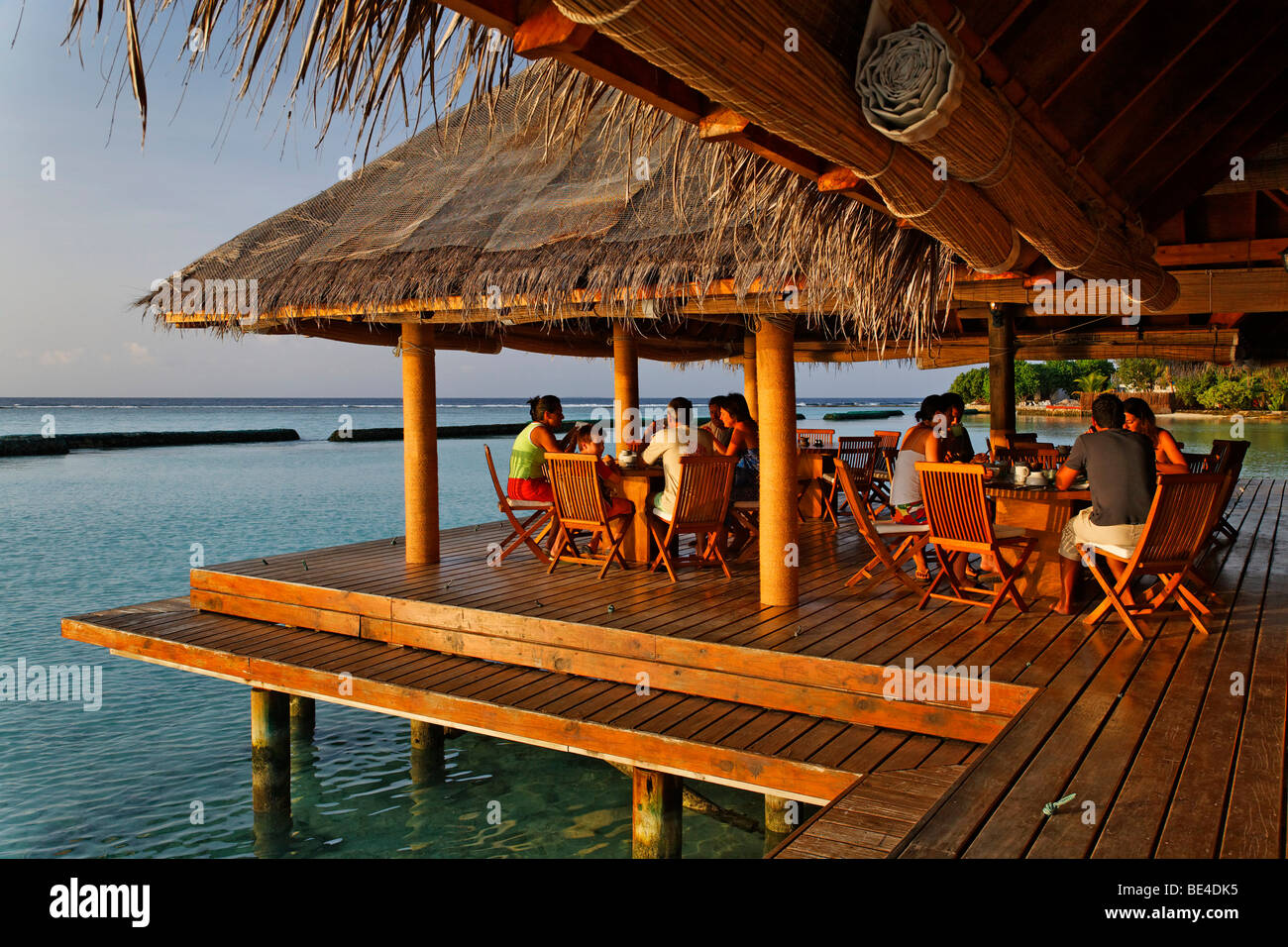 People at breakfast in open restaurant, roof with palm fronds ...