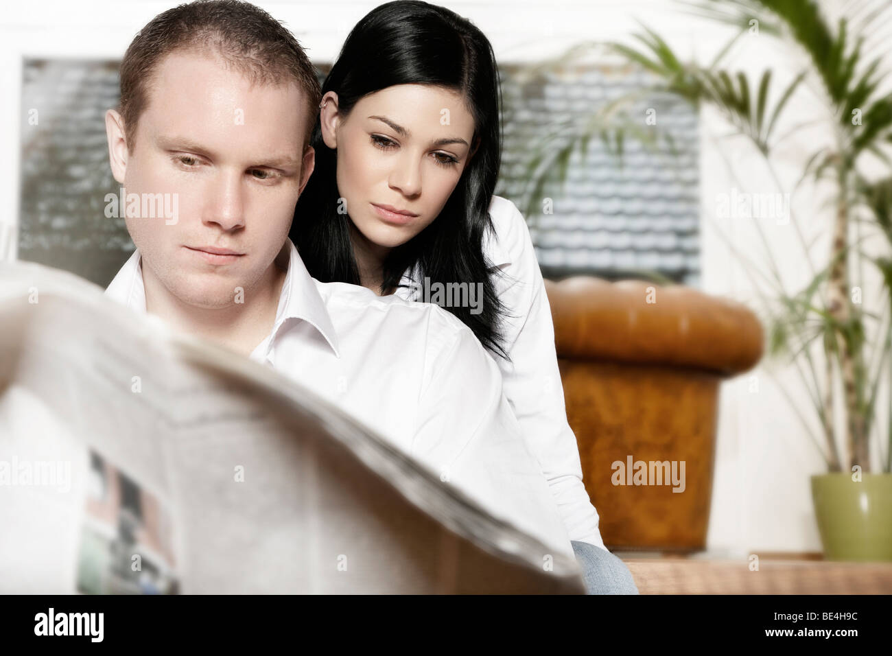 Young couple reading a newspaper together Stock Photo - Alamy