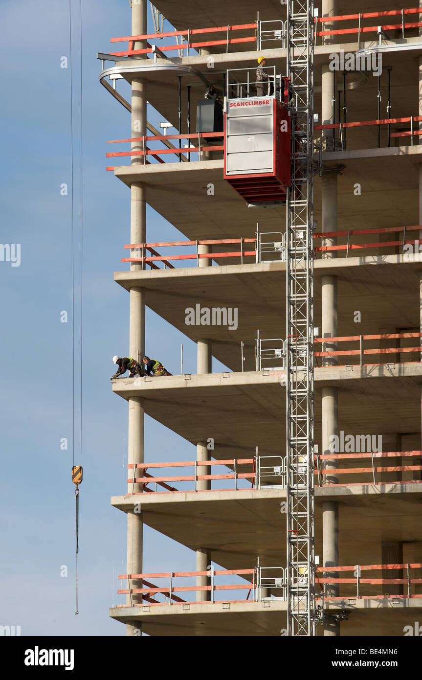 Construction workers fitting safety rails to s partly built office ...