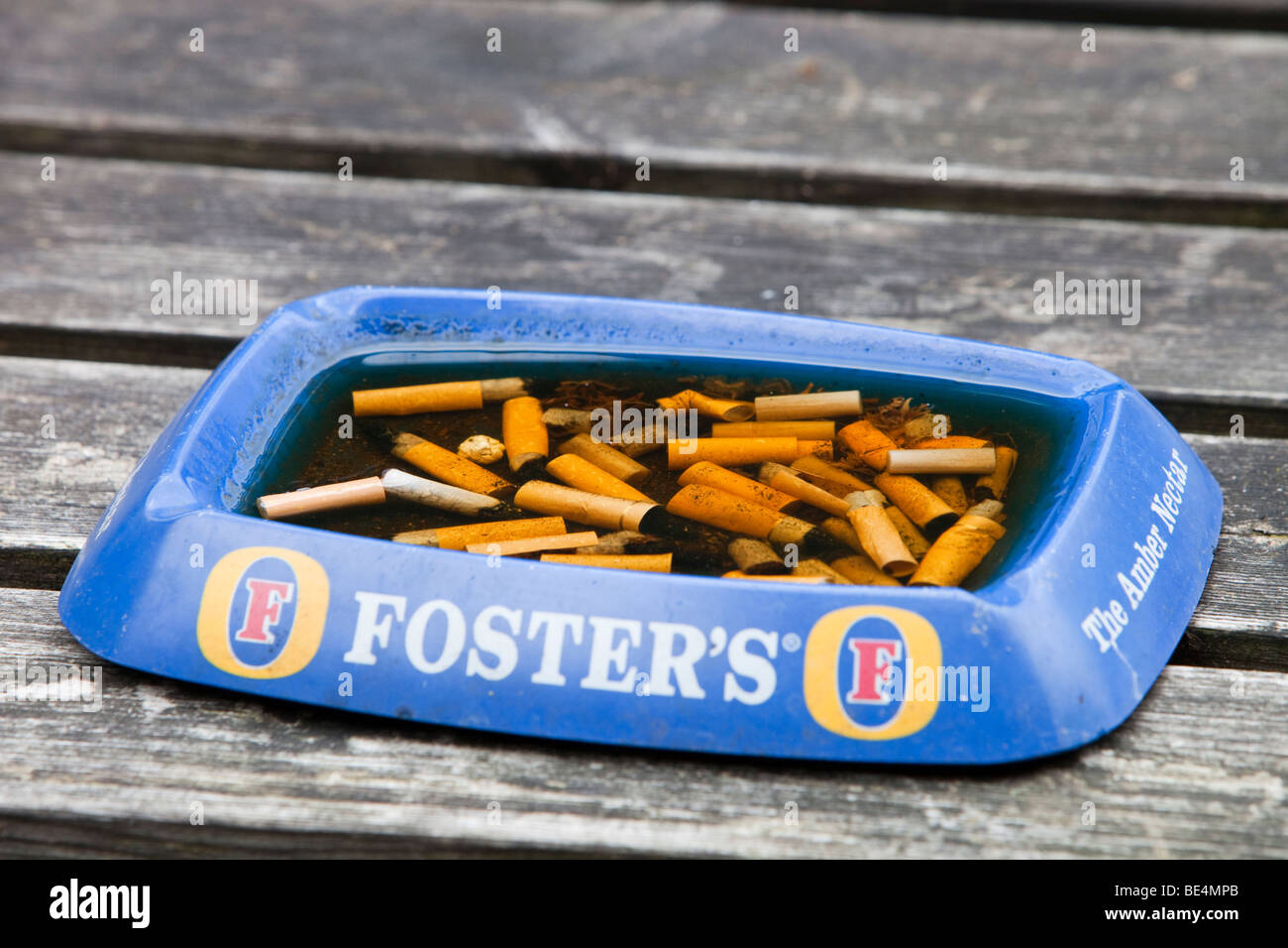 Cigarettes in an ash tray outside a pub filled with rain water Stock ...