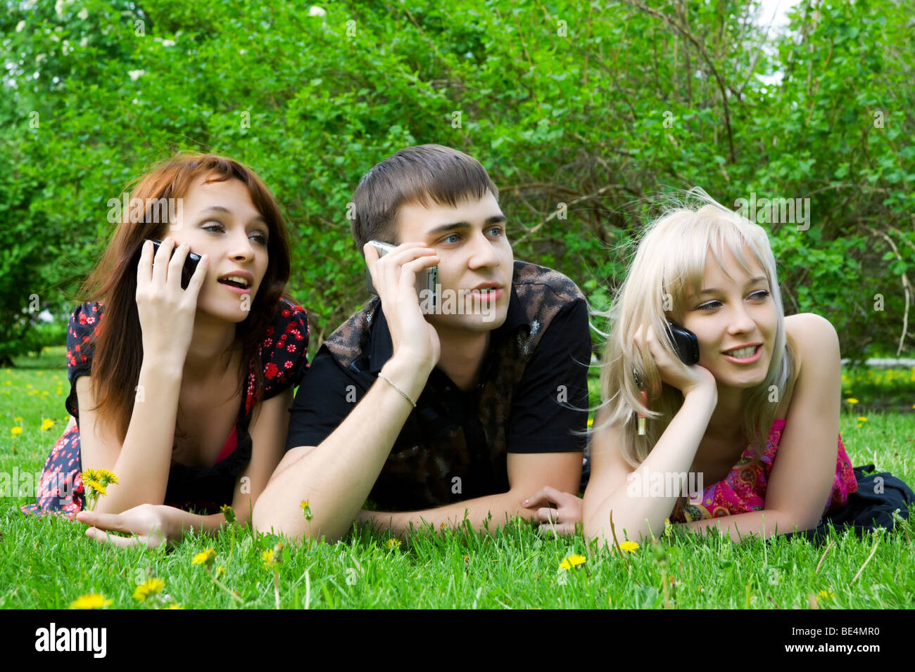 Three young friends are calling on mobile phones Stock Photo - Alamy
