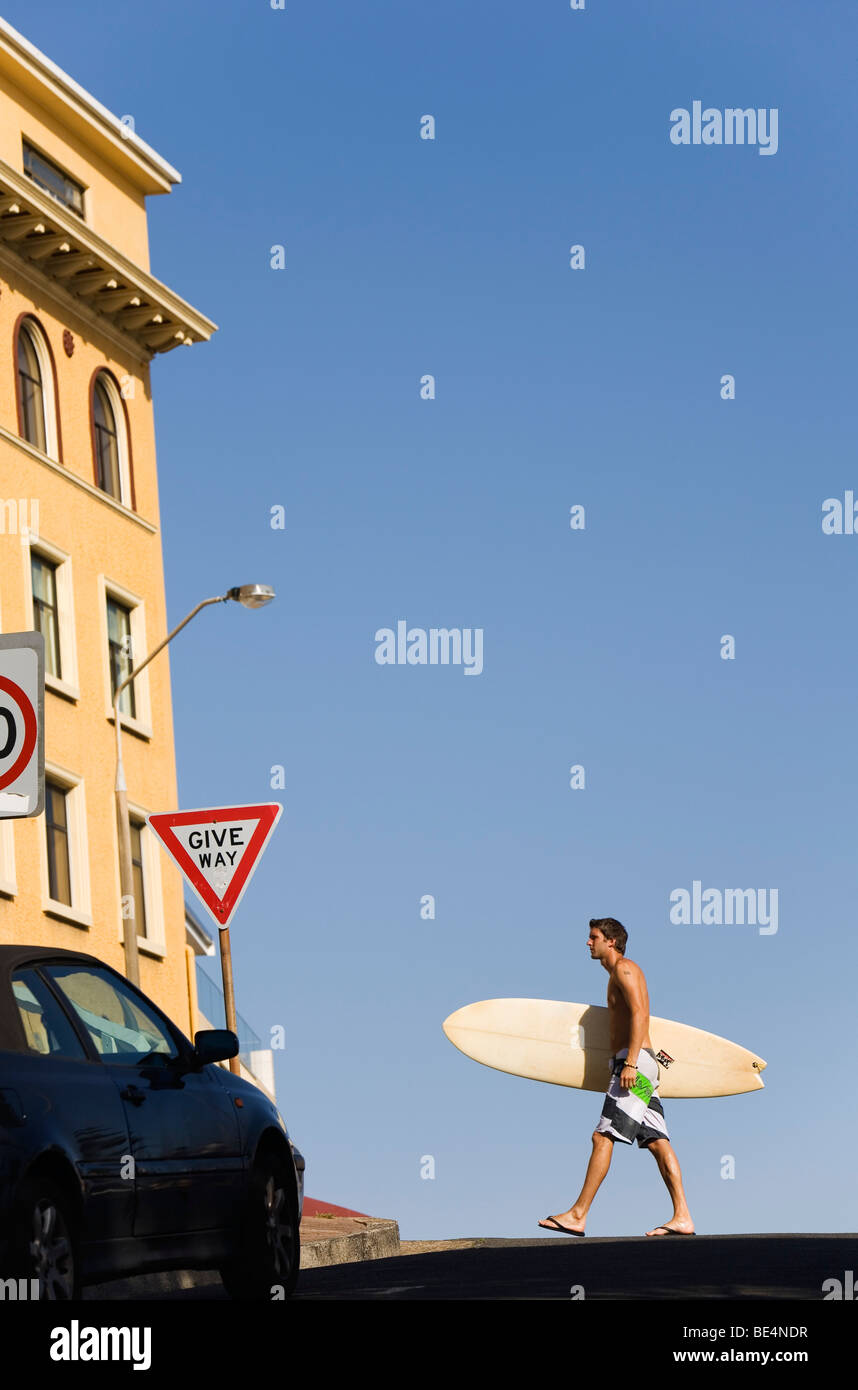 Man carrying surfboard along road at Bondi Beach. Sydney, New South ...