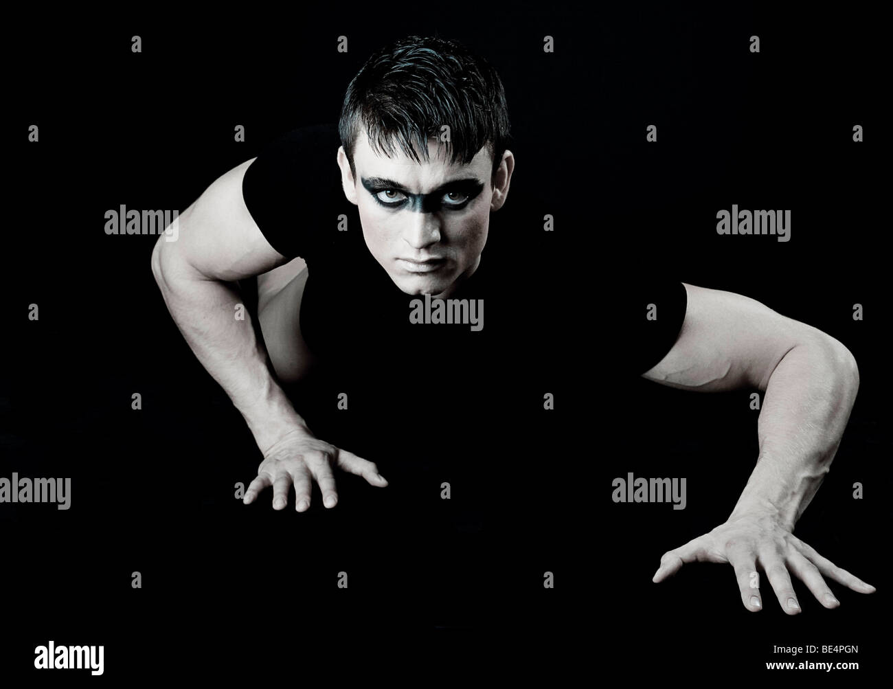 Young man, crawling on the ground, black T-shirt, with eye make-up ...