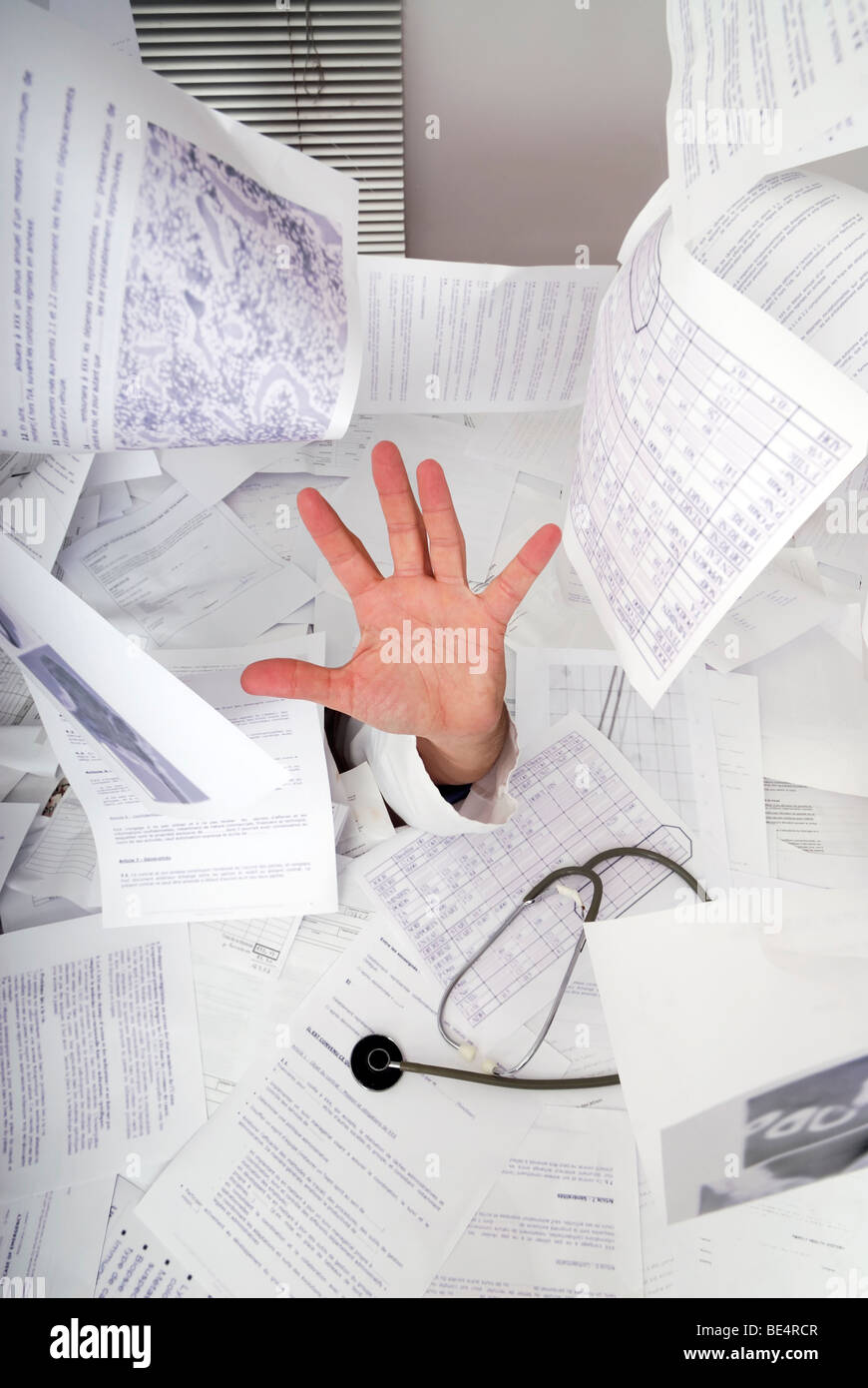 hand of doctor sticking out of a desk full of papers Stock Photo - Alamy