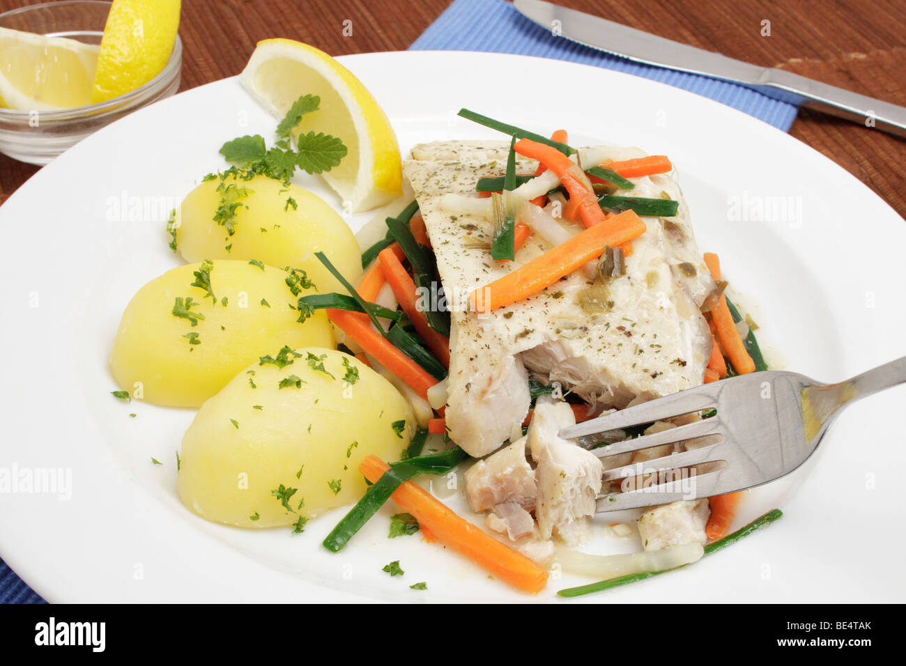 Steamed Saithe fillet on a bed of colourful vegetables with boiled ...