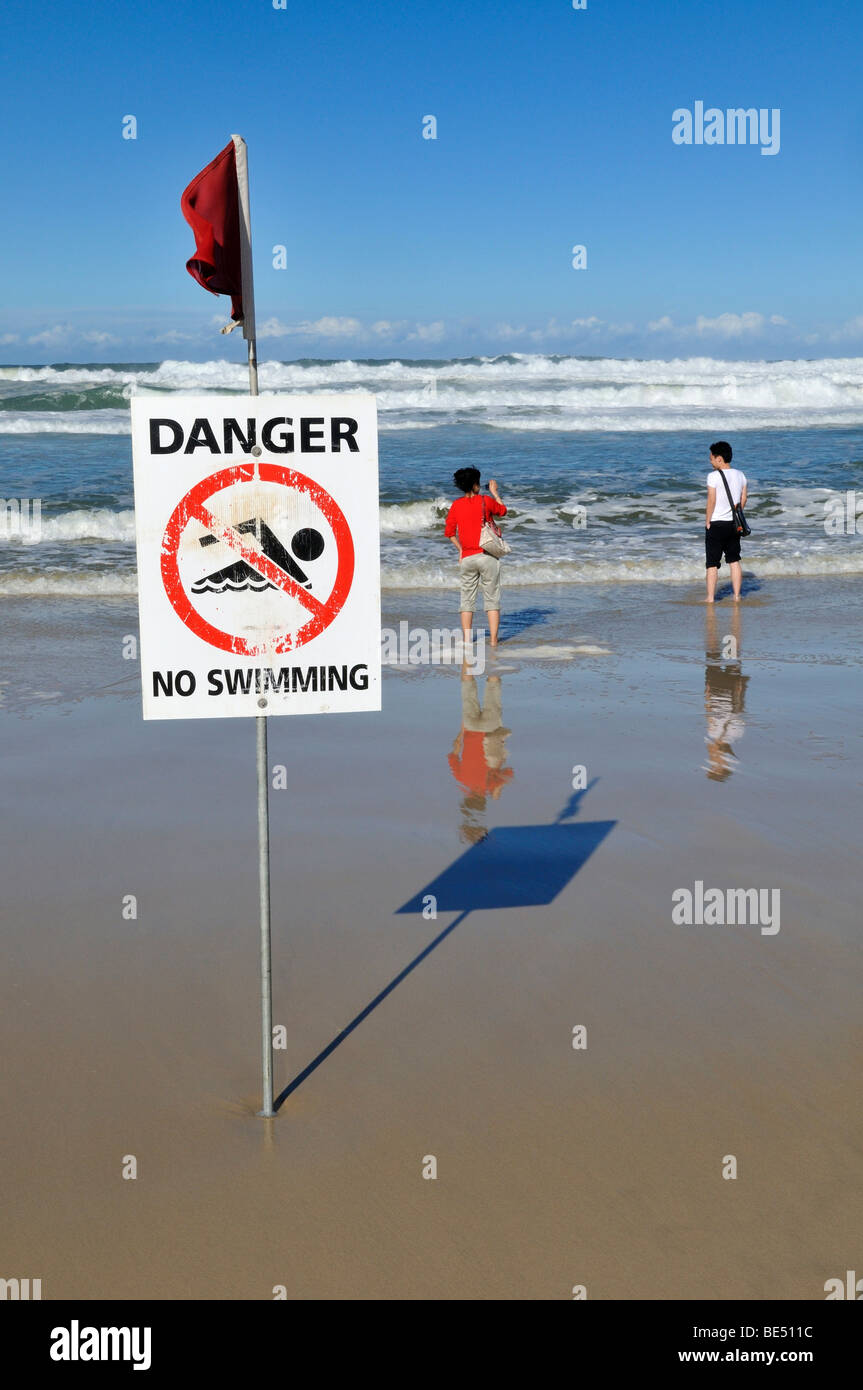 Lifeguard warning sign with tourists on the beach of Surfers Paradise ...