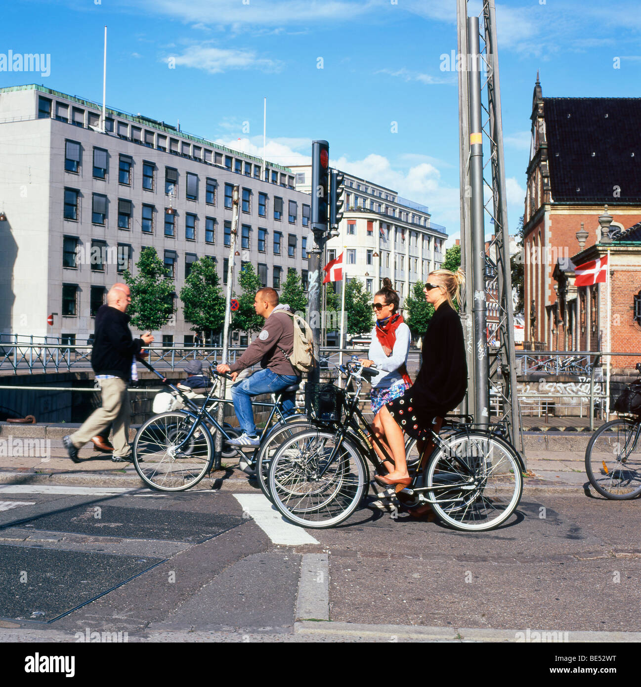 Stylish female commuter cyclist waiting with group of people on bikes ...