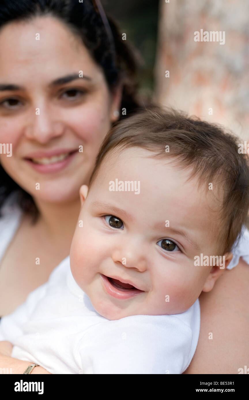 Hispanic mother in her thirties holds her six month old baby boy. Model ...