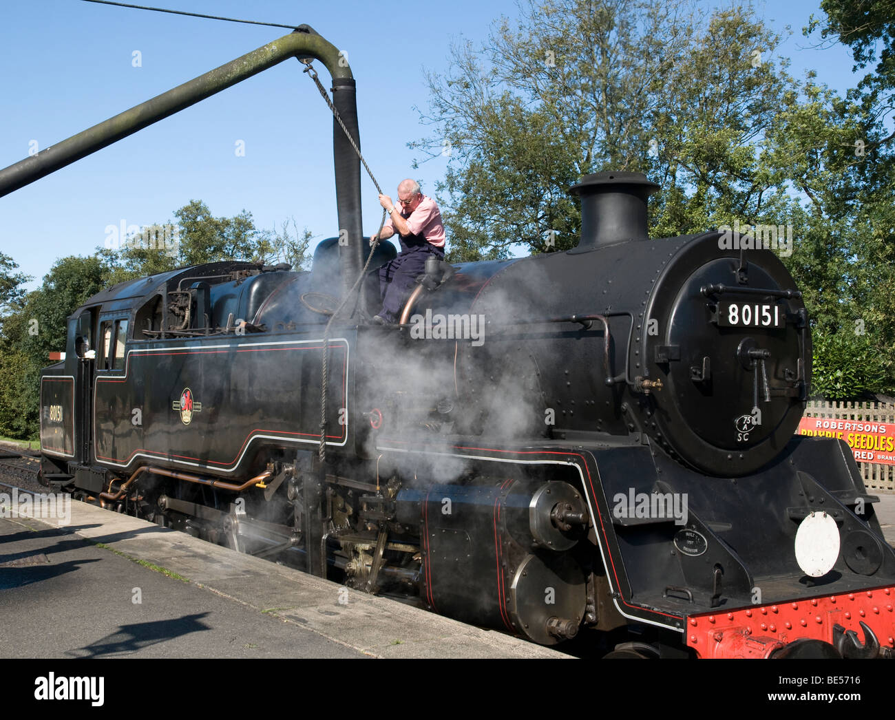 A man refilling the water on a steam engine at the Bluebell railway at ...
