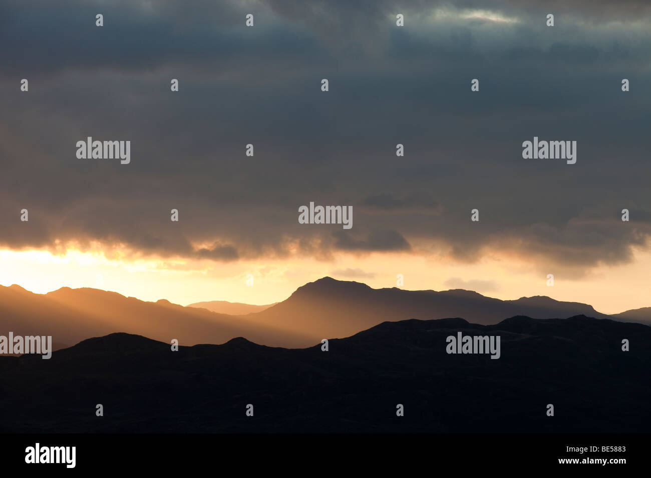 Shafts of light from the setting sun over the Lake District mountains ...