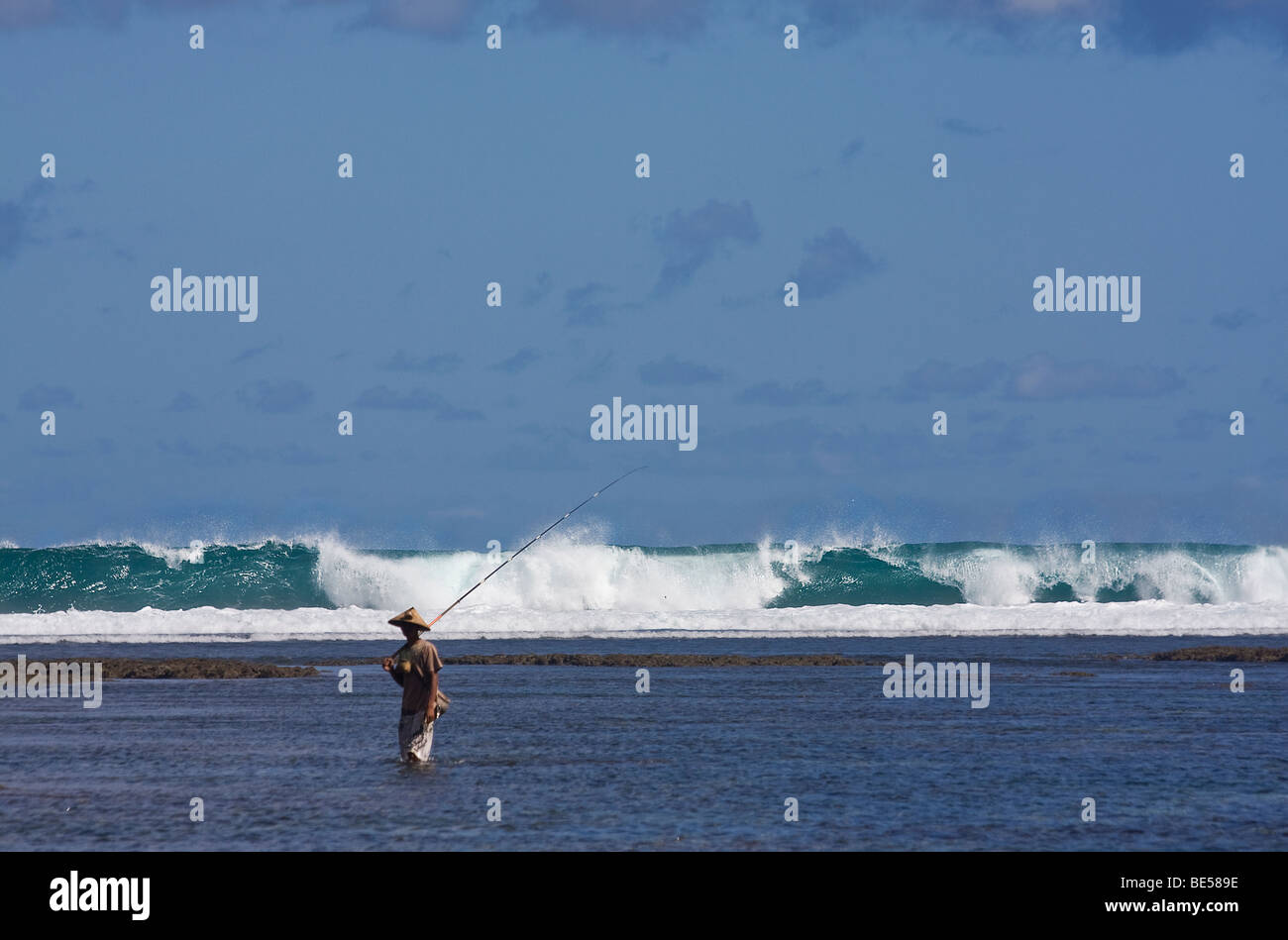 Fisherman with conical hat fishing sheltered by the coral reef with big ...