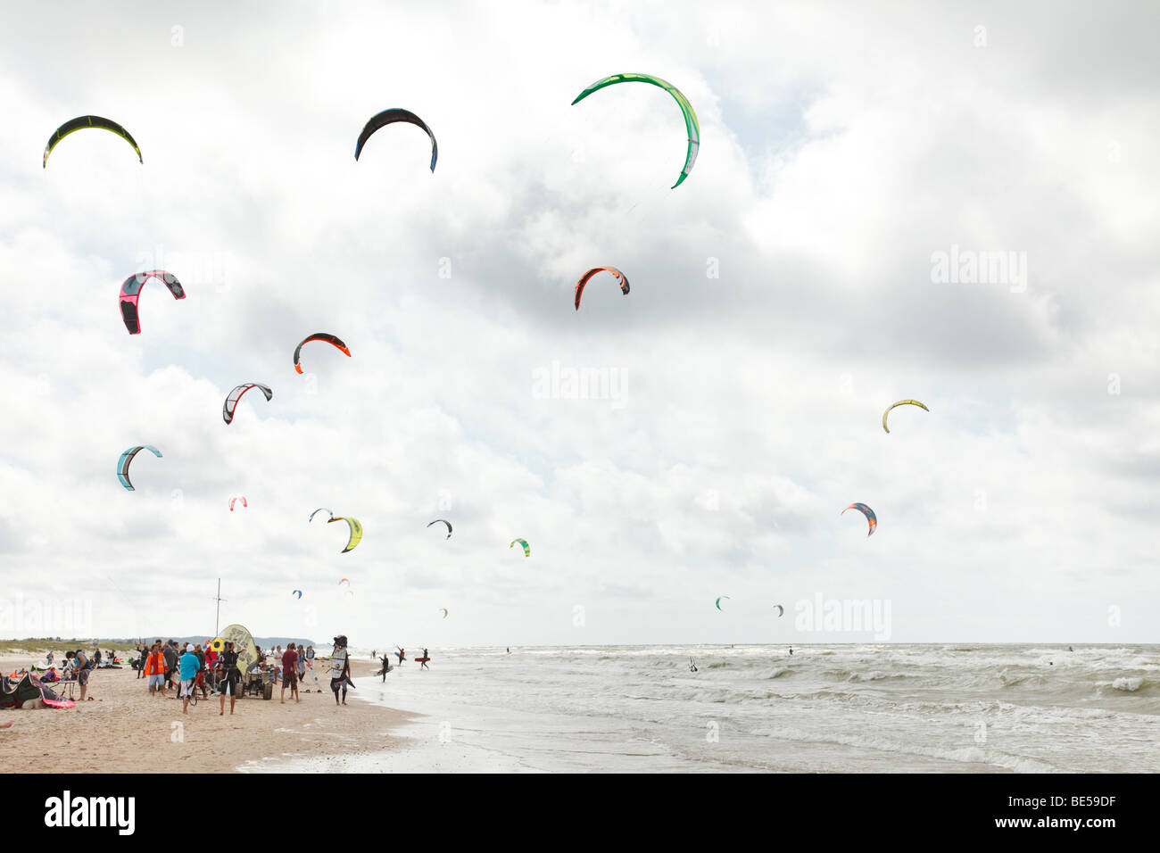 Kiteboarding competition with many active people and kites flying high ...