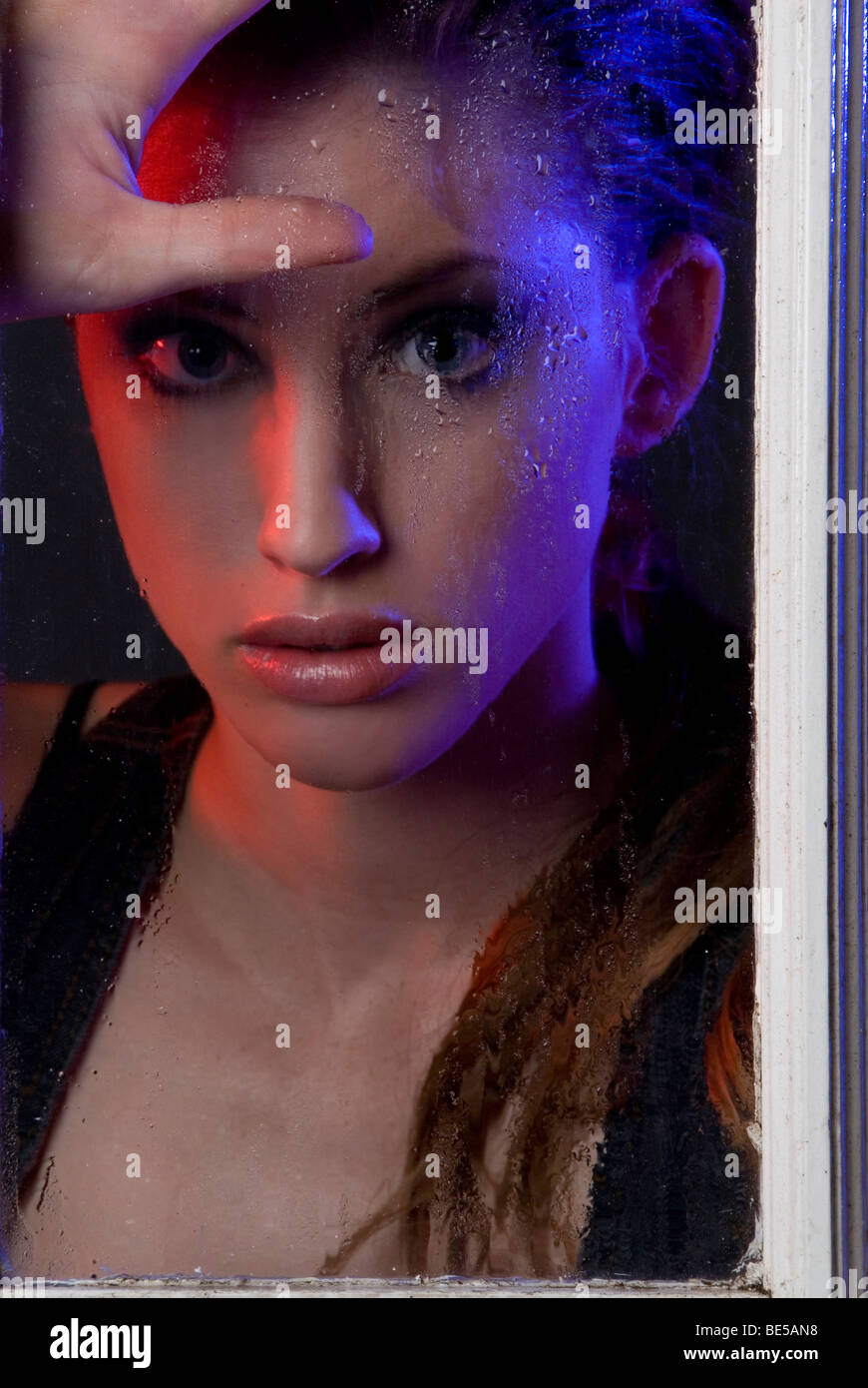Young woman looking through window Stock Photo - Alamy