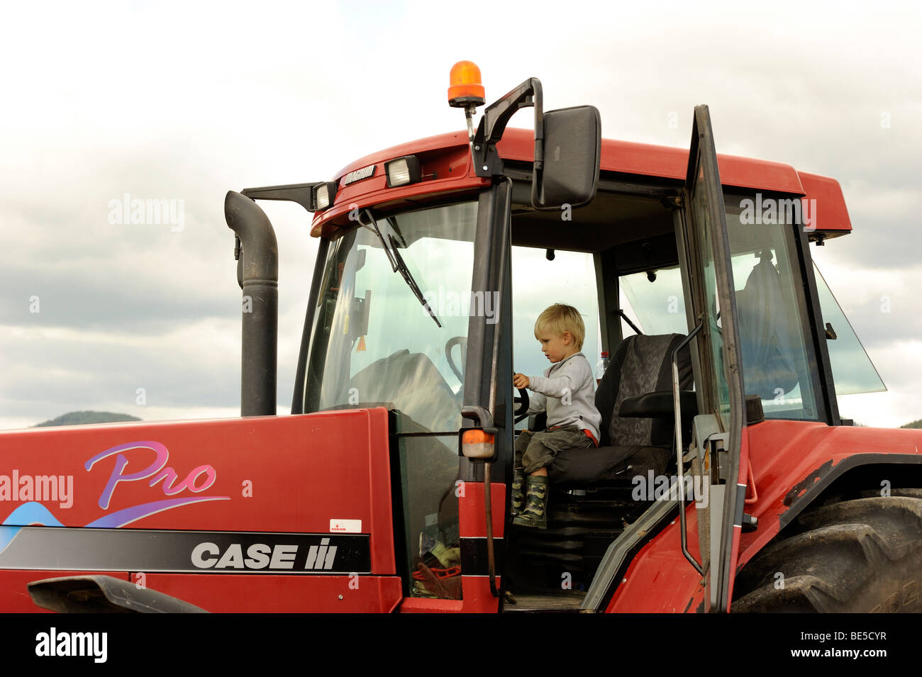 Child blond Boy driving a vintage tractor engine Stock Photo - Alamy