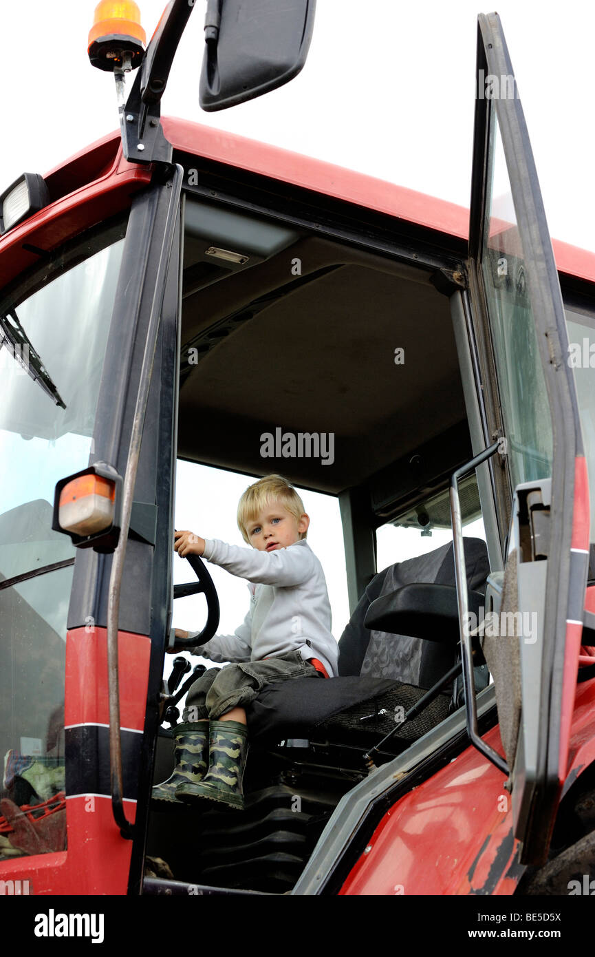 Child blond Boy driving a vintage tractor engine Stock Photo - Alamy