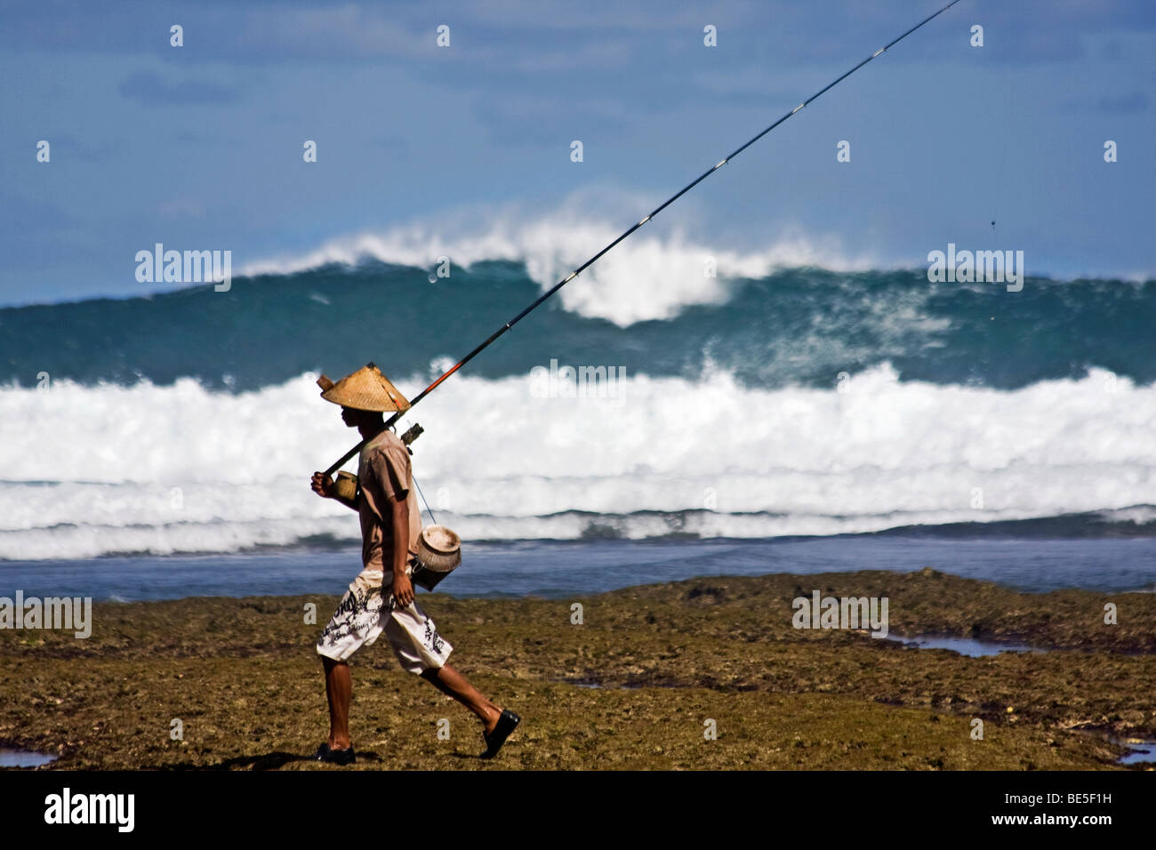 Fisherman with conical hat fishing sheltered by the coral reef with big ...