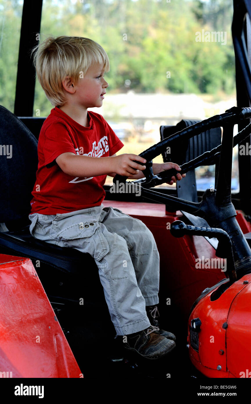 Child blond Boy driving a vintage tractor engine Stock Photo - Alamy