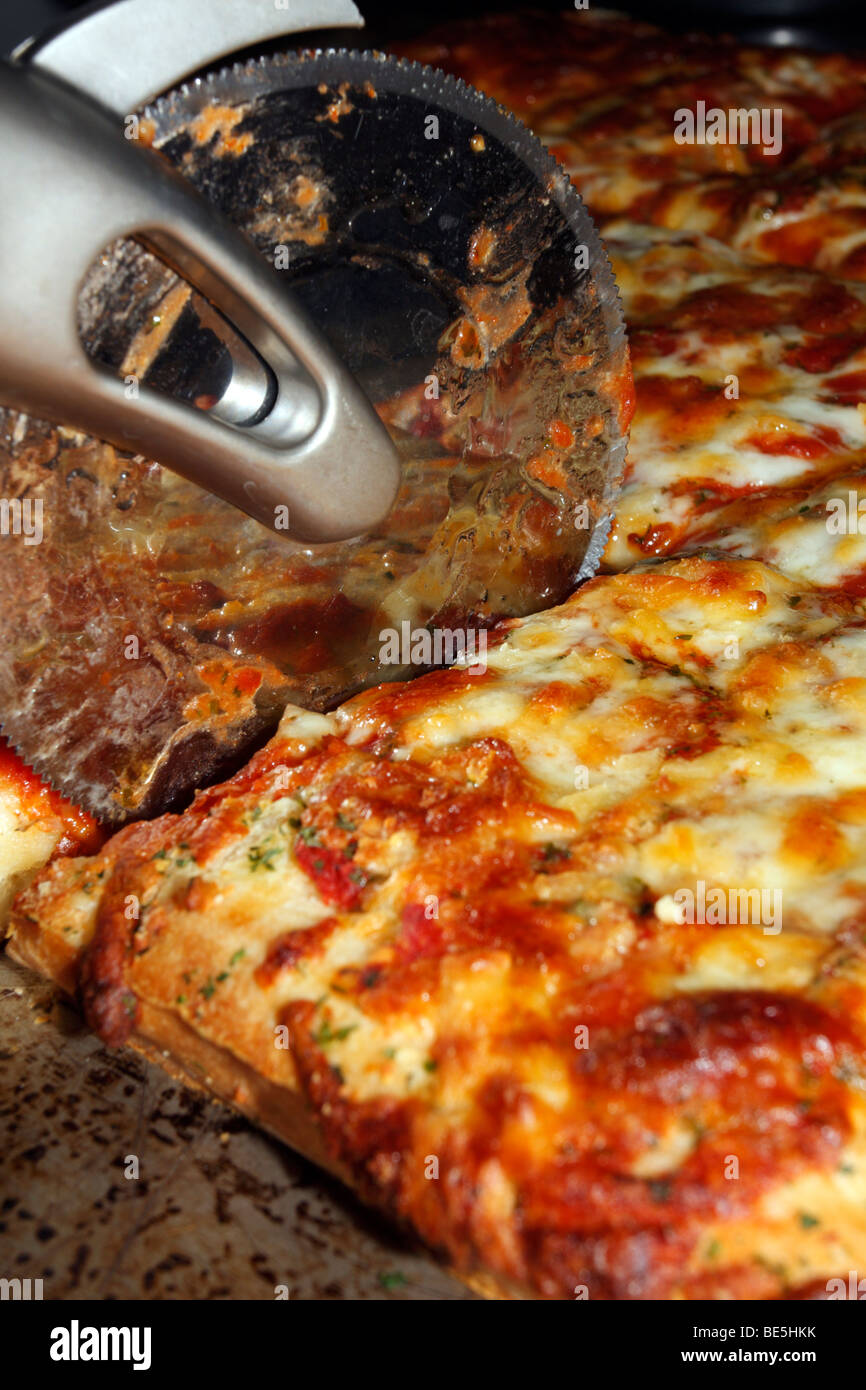 Freshly cooked pizza being cut with round cutter Stock Photo - Alamy