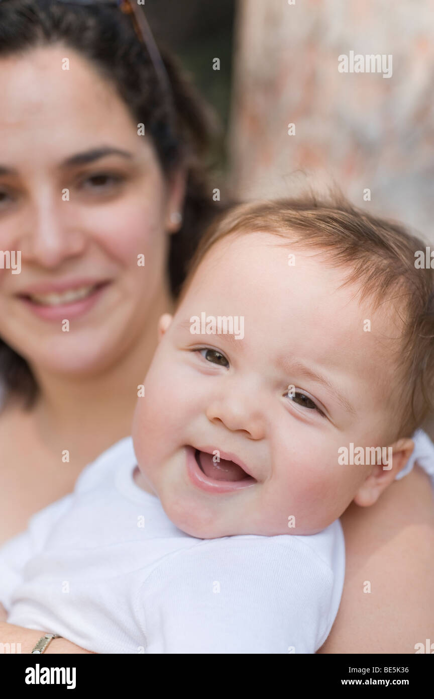 Hispanic mother in her thirties holds her six month old baby boy. Model ...