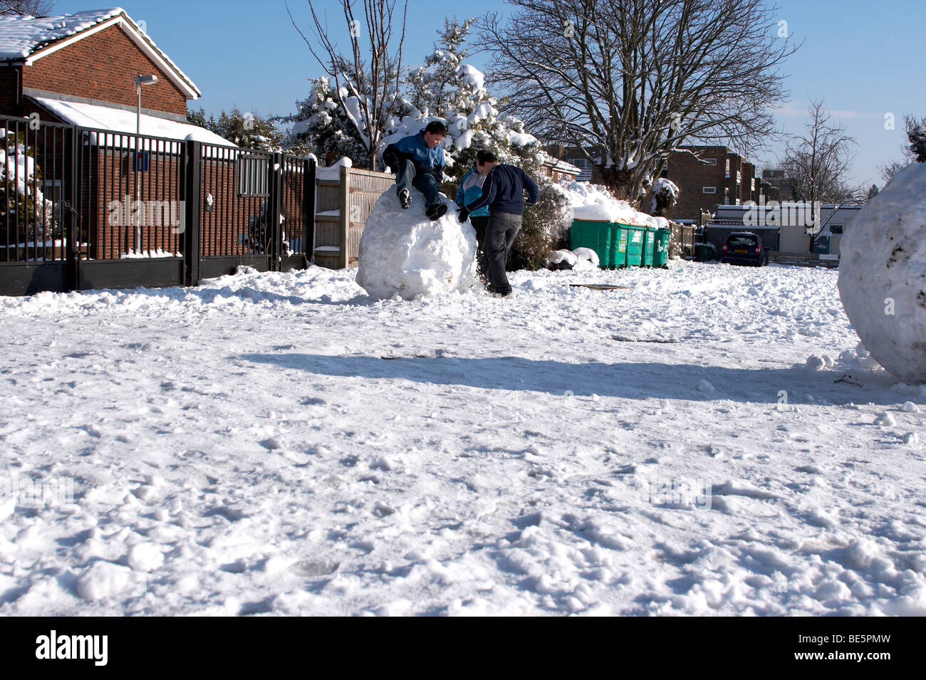 Tree boys building a snowman Stock Photo - Alamy