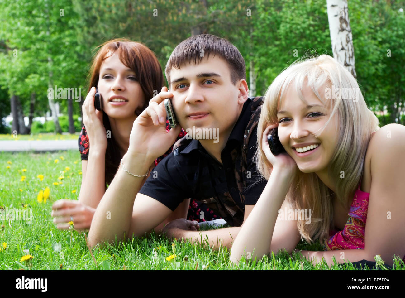 Three young friends are calling on mobile phones Stock Photo - Alamy