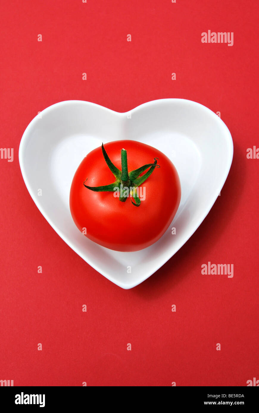 Individual vine tomato in a heart-shaped porcelain bowl Stock Photo - Alamy