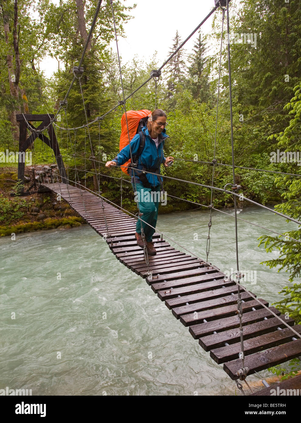 Woman, female hiker with backpack crossing suspension bridge across ...