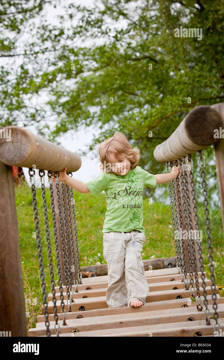 Boy, 3 years old, running across a chain bridge at a playground Stock ...