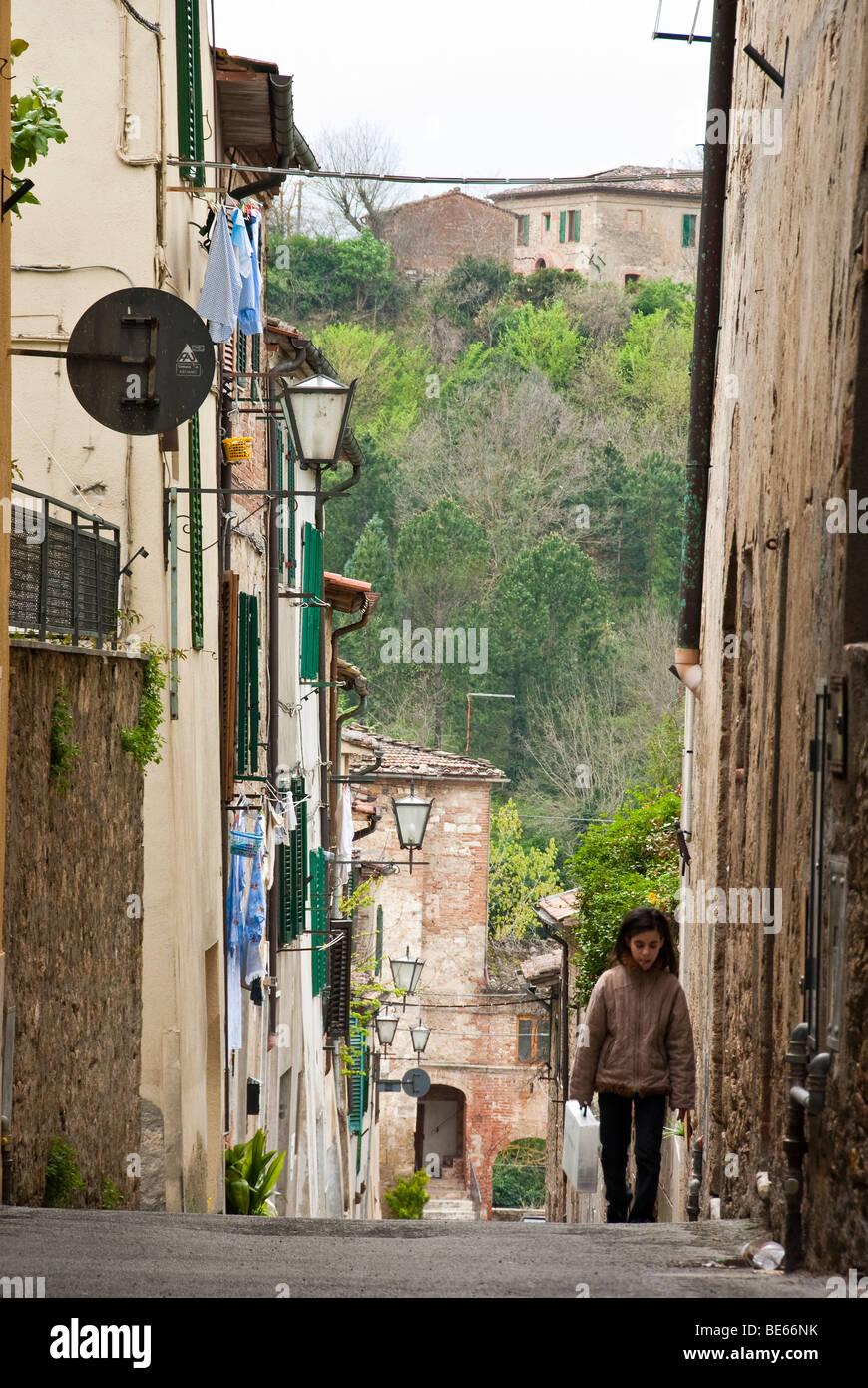 Italian girl walking up a street in the town of Asciano in the province ...
