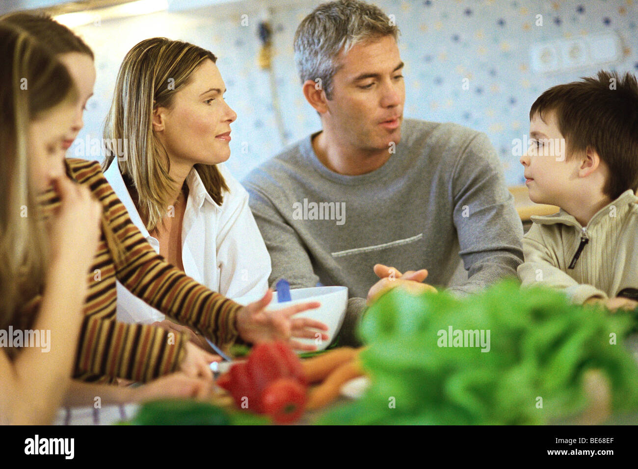 Family together in kitchen, raw vegetables on counter Stock Photo - Alamy