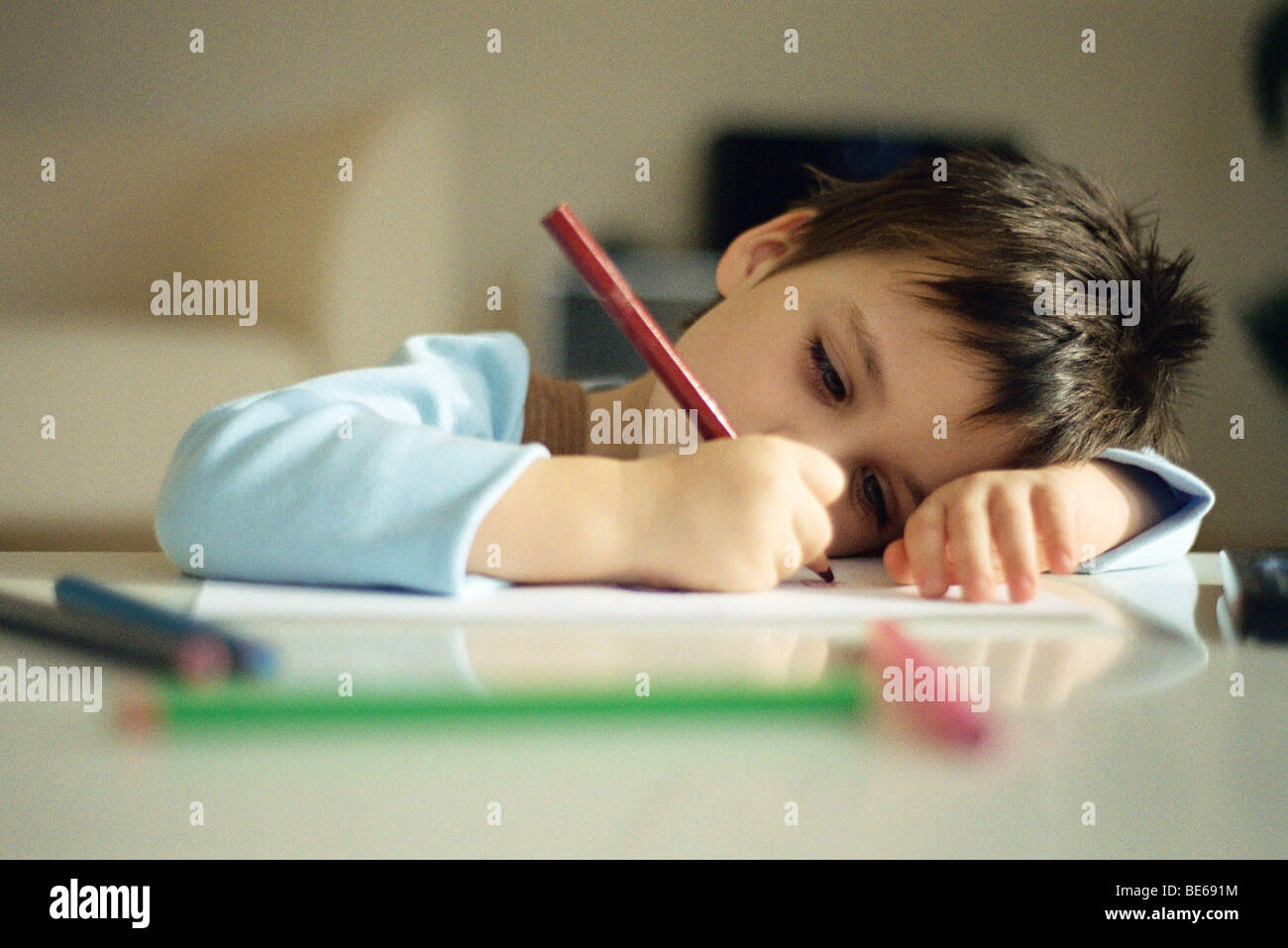 Little boy resting head on arm, drawing with colored pencils Stock ...