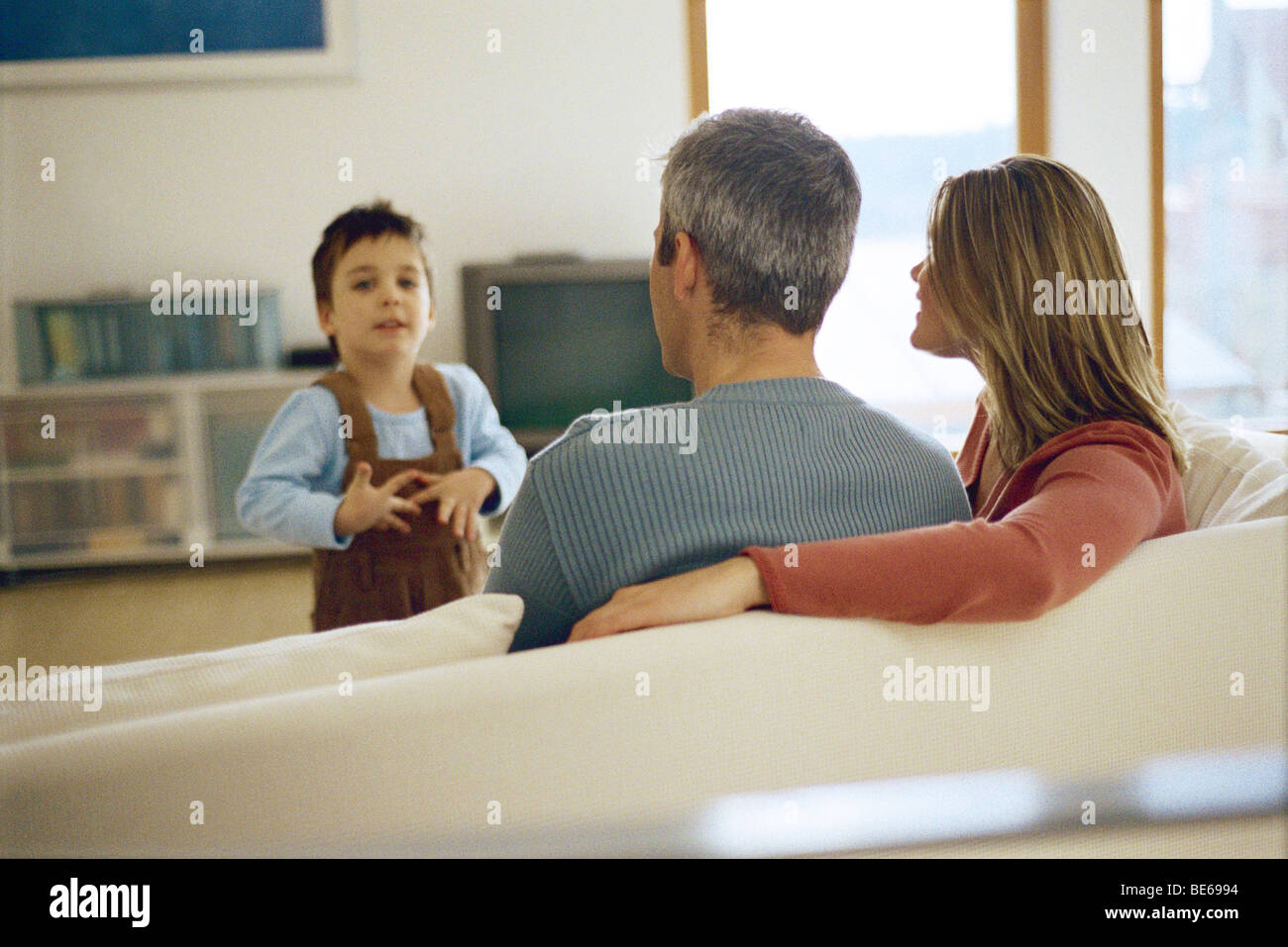 Little boy talking to his parents sitting on the sofa Stock Photo - Alamy