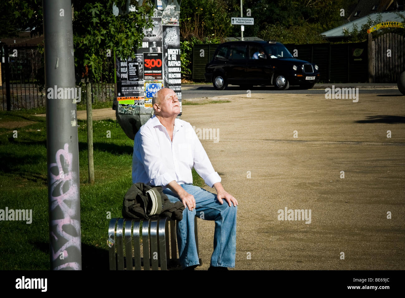 A man sitting on a bench in the street, enjoying the sunshine Stock ...