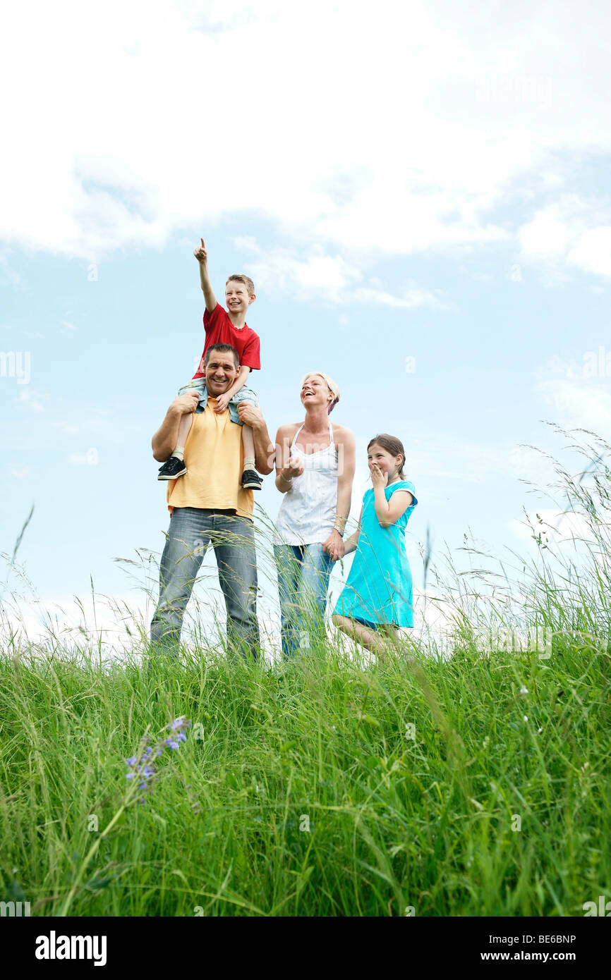 Happy family standing on a meadow, looking into the distance Stock ...
