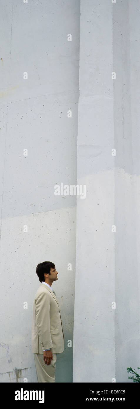 Businessman standing stiffly beside high wall, side view Stock Photo ...