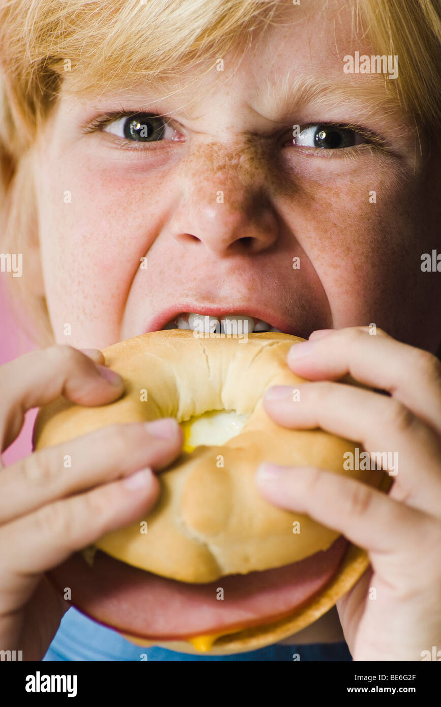 Boy biting into ham and cheese bagel sandwich, close-up Stock Photo - Alamy