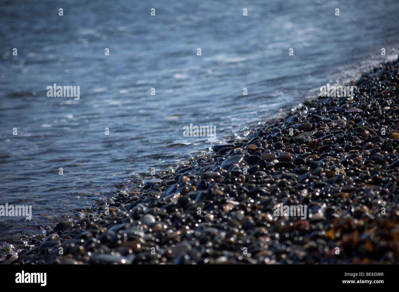 Diagonal view of ocean ripples and wet pebbles Stock Photo - Alamy