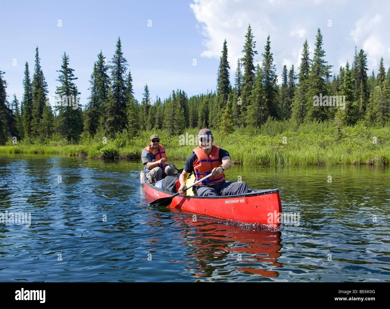 Two young men canoeing, paddling, upper Liard River, Caribou Creek ...